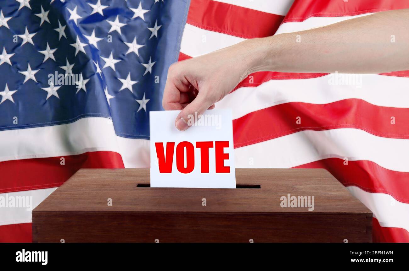 Human hand inserting bulletin in ballot box on USA National Flag ...