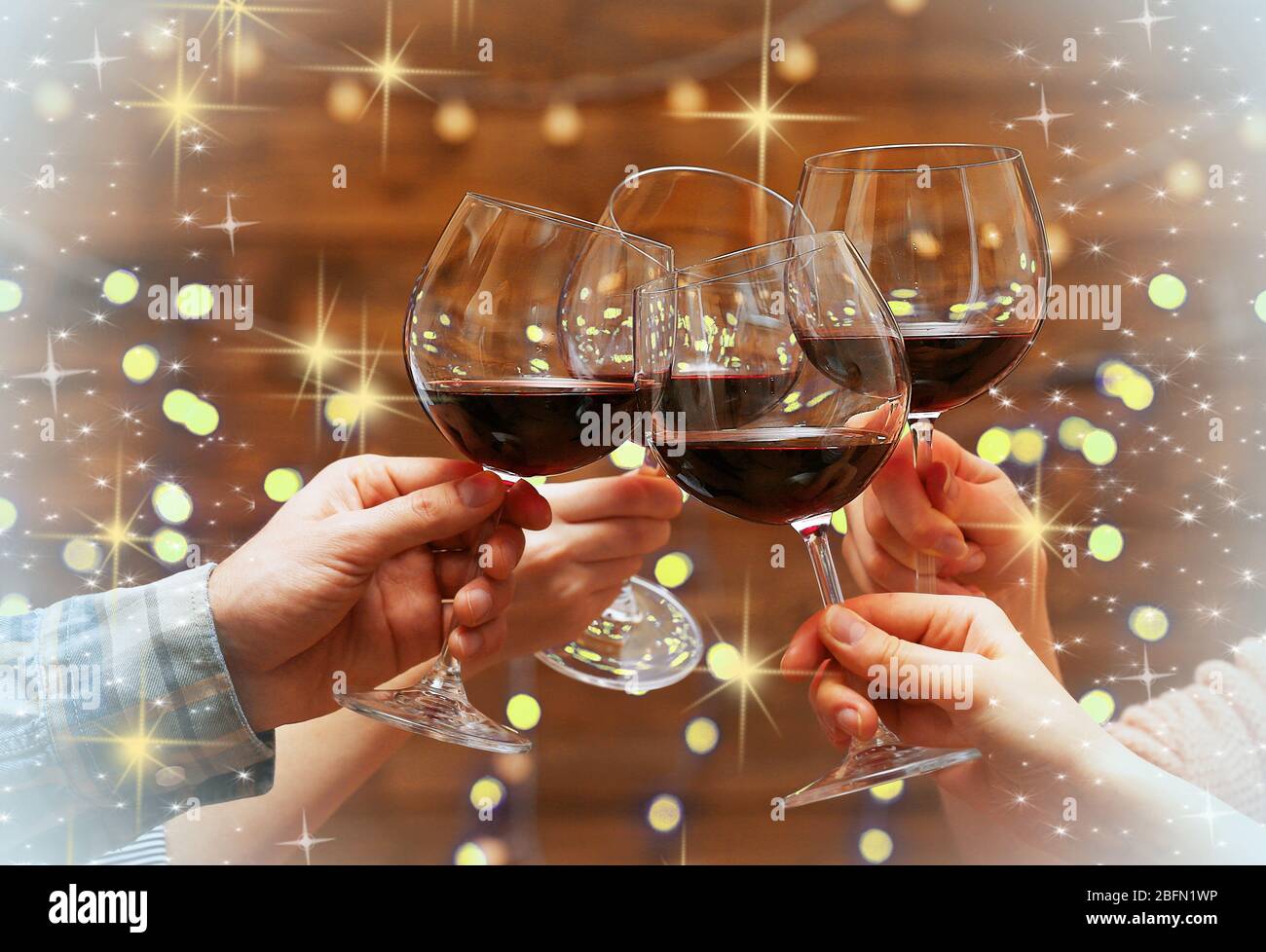 Clinking glasses of red wine in hands on bright lights background with ...