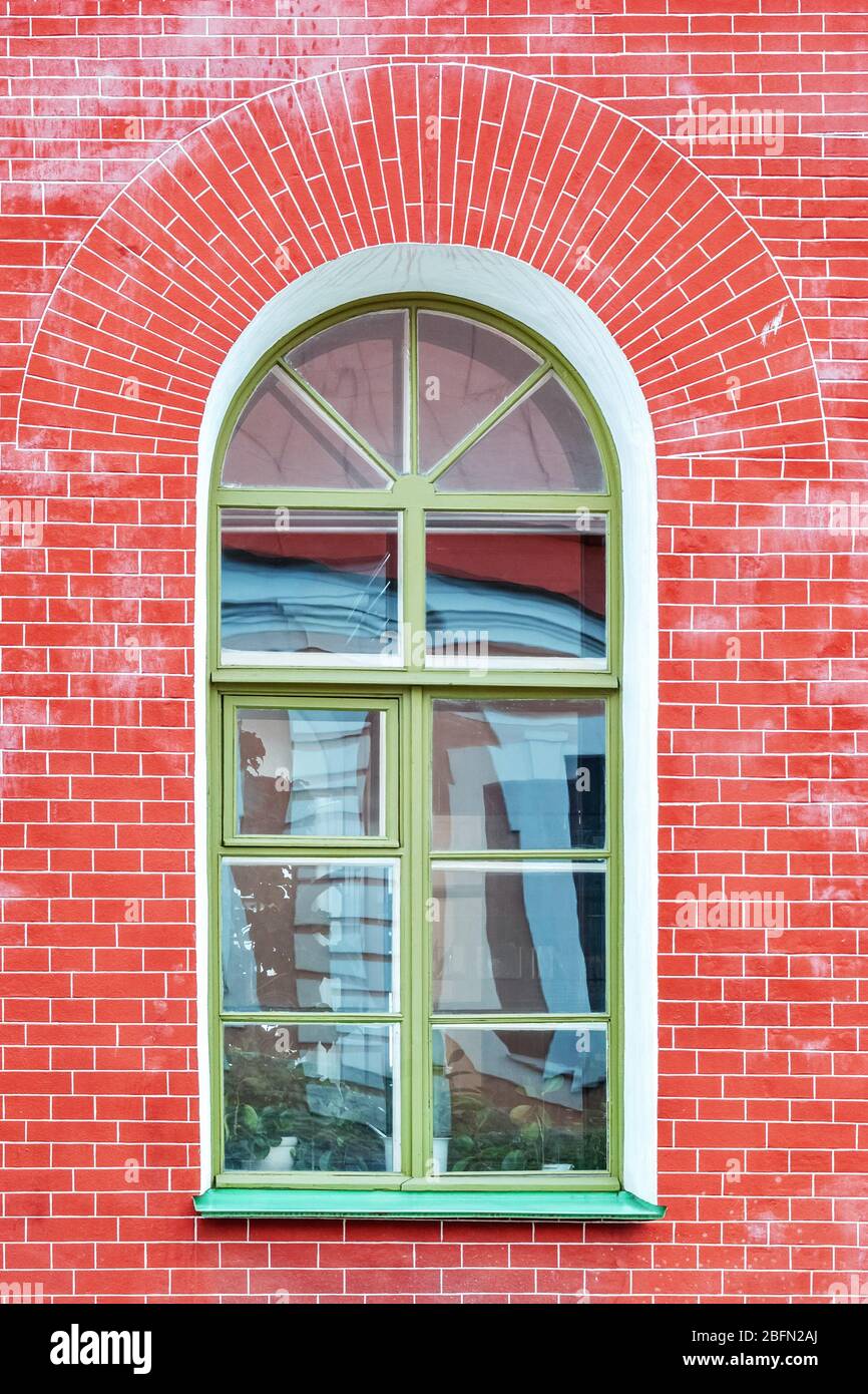 Window with an arch and a green windowsill on a background of red brick ...