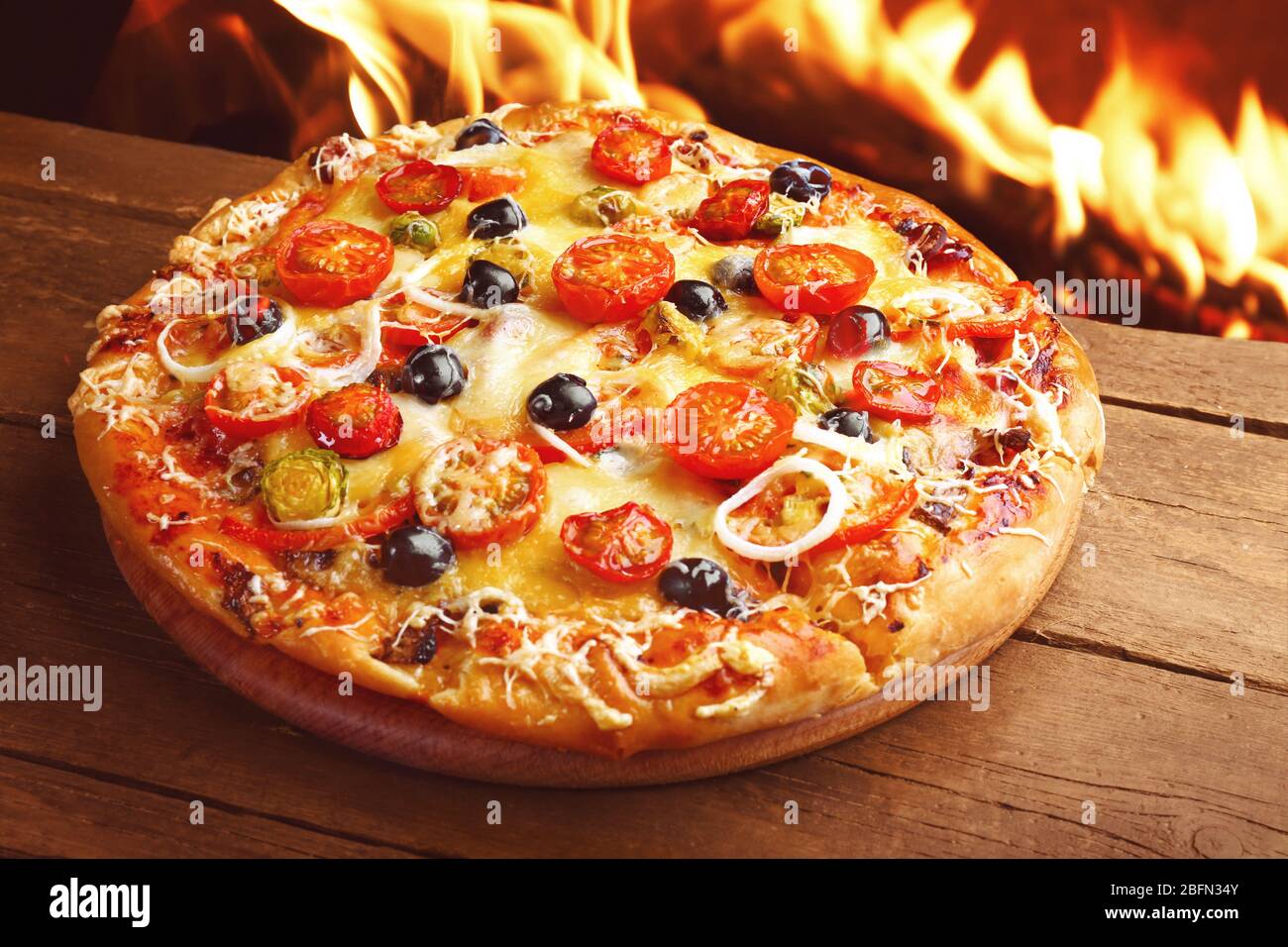 Delicious hot pizza on wooden table against fire flame background Stock ...