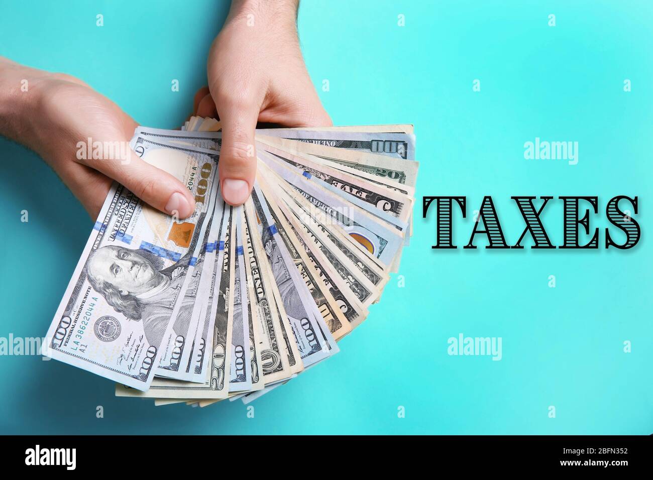 Male hands holding dollar banknotes against turquoise background.Taxes ...