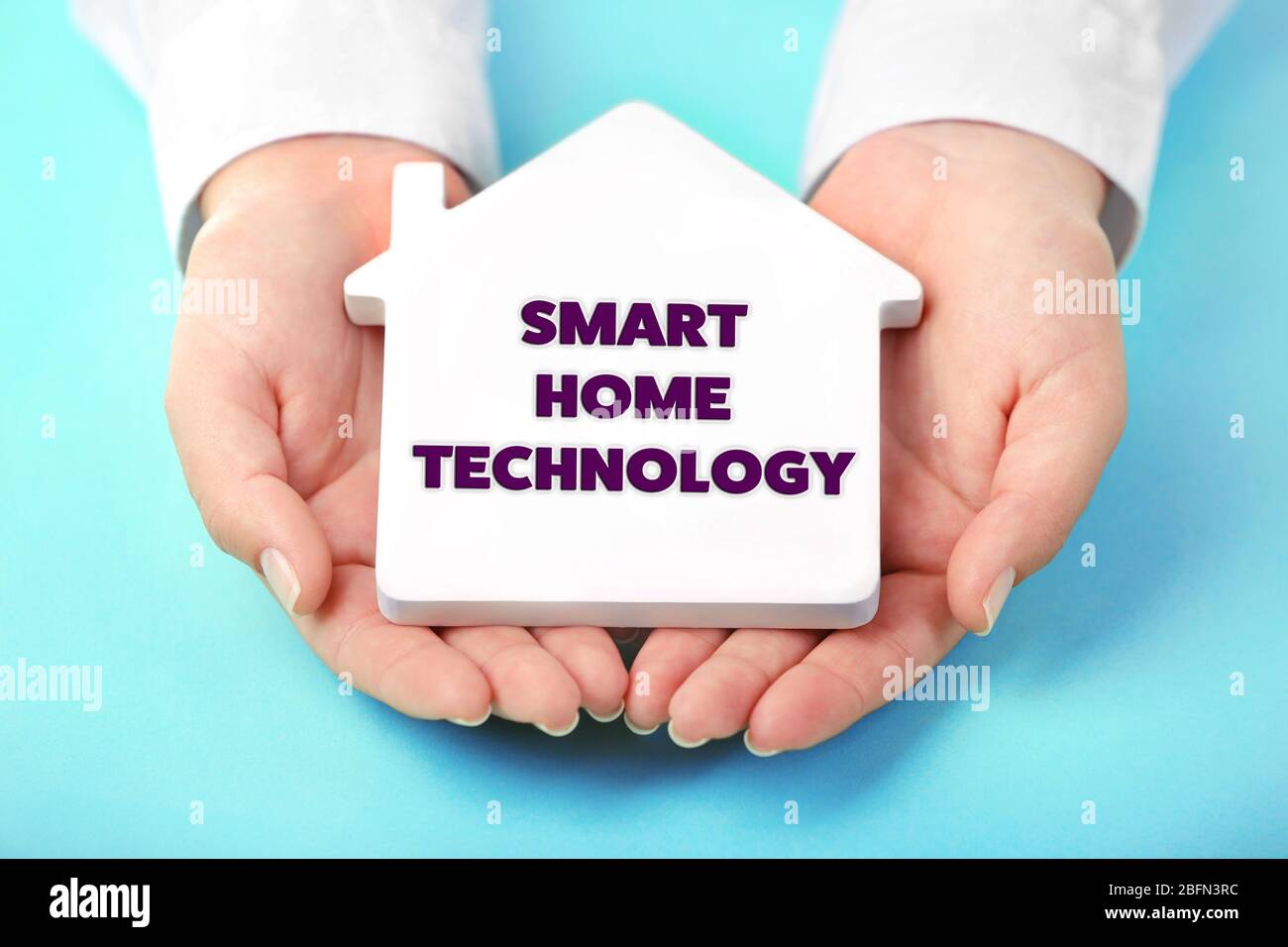 Smart home technology concept. Female hands holding house on turquoise ...