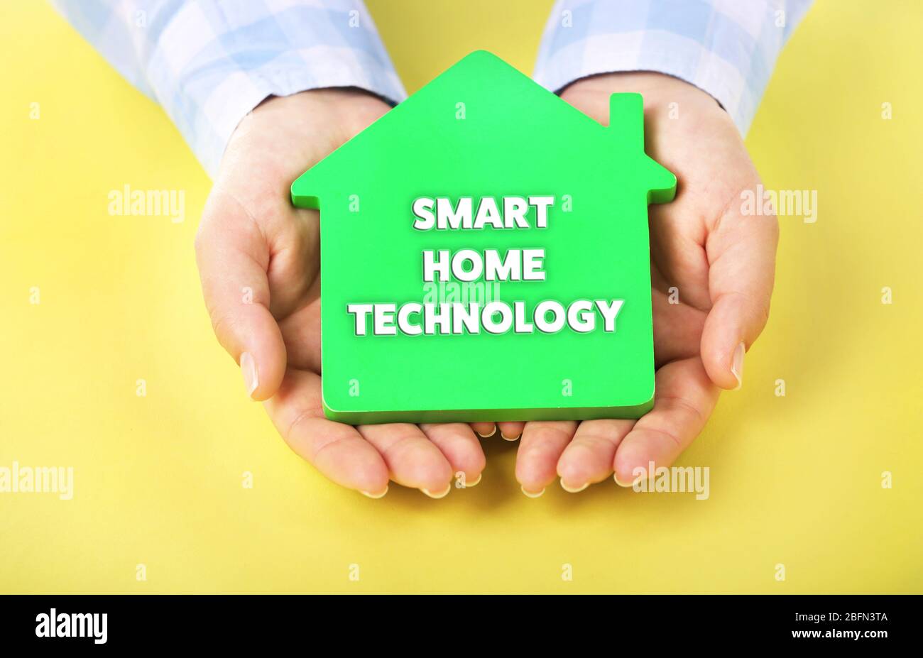 Smart home technology concept. Female hands holding house on yellow ...