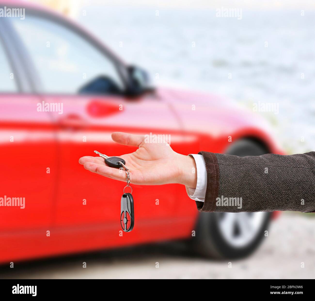 Male hand holding car keys against car background Stock Photo - Alamy