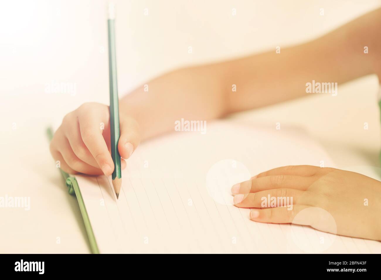 Children hand with pencil writing on notebook Stock Photo - Alamy
