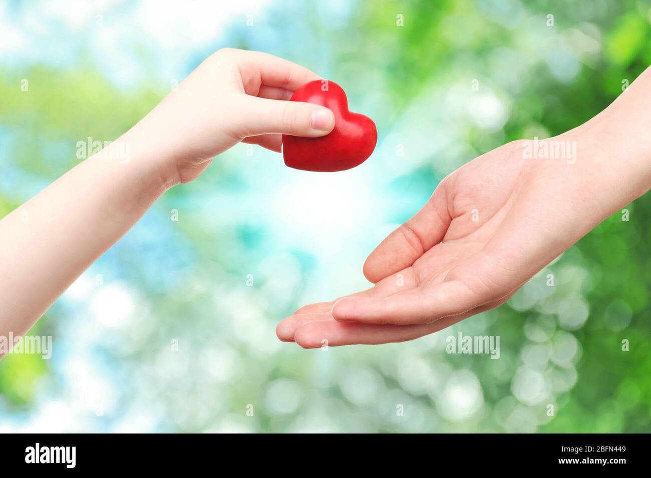 Heart in child and mother hands on green nature background. Concept of ...