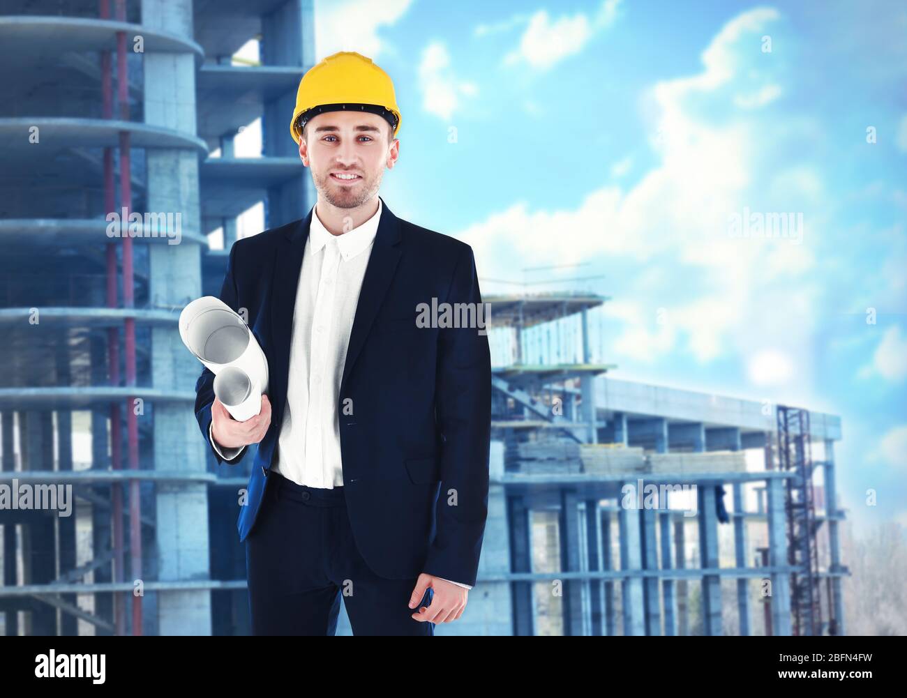 Professional engineer with blueprint on blurred construction site ...