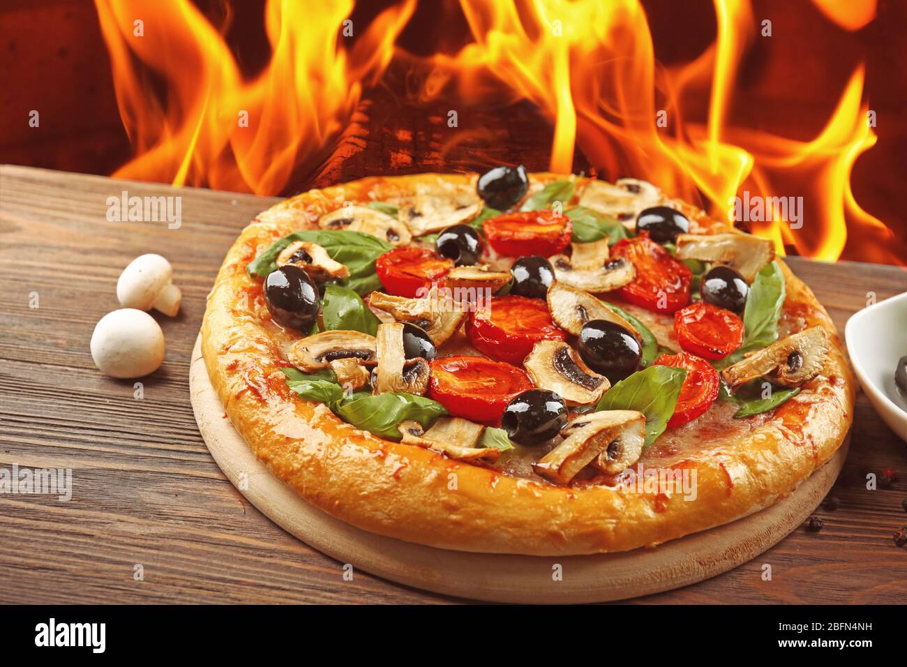 Delicious hot pizza on wooden table against fire flame background Stock ...