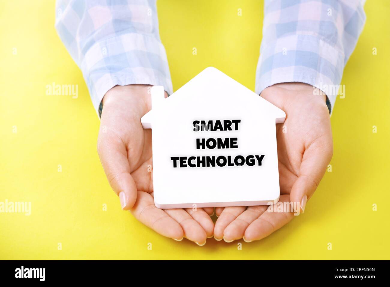 Smart home technology concept. Female hands holding house on yellow ...