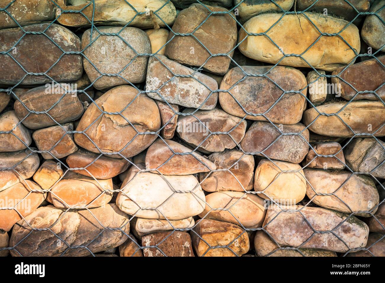 colored stones stacked and held by a wire fence Stock Photo - Alamy