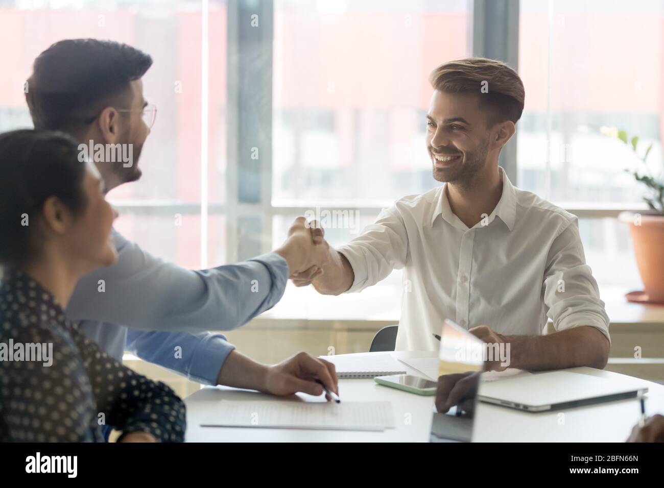 Smiling businessmen get acquainted shaking hands at meeting in office ...