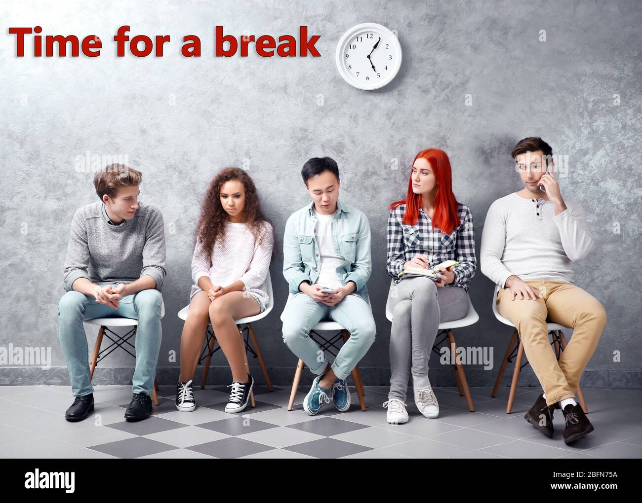 Young people sitting on a chairs in grey hall Stock Photo - Alamy