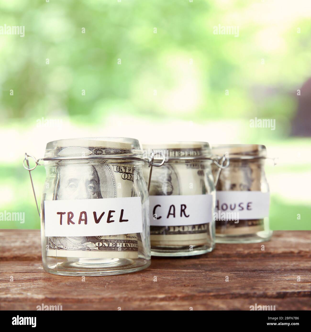 Three jars for different needs full of banknotes on nature background ...