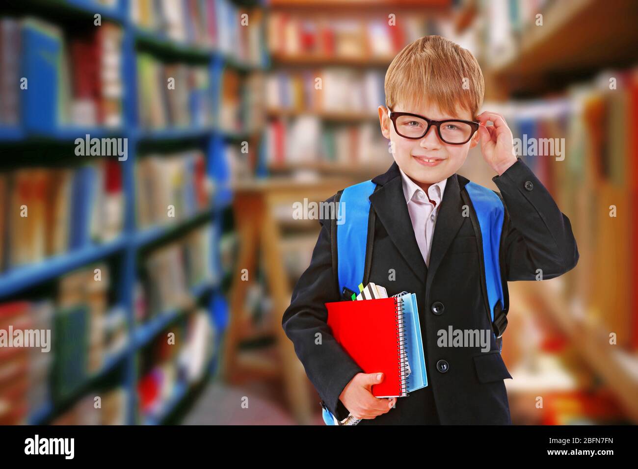 Boy with books in school library Stock Photo - Alamy