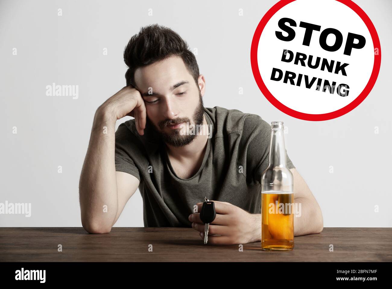 Drunk young man with car key and beer bottle at bar. Sign with text ...