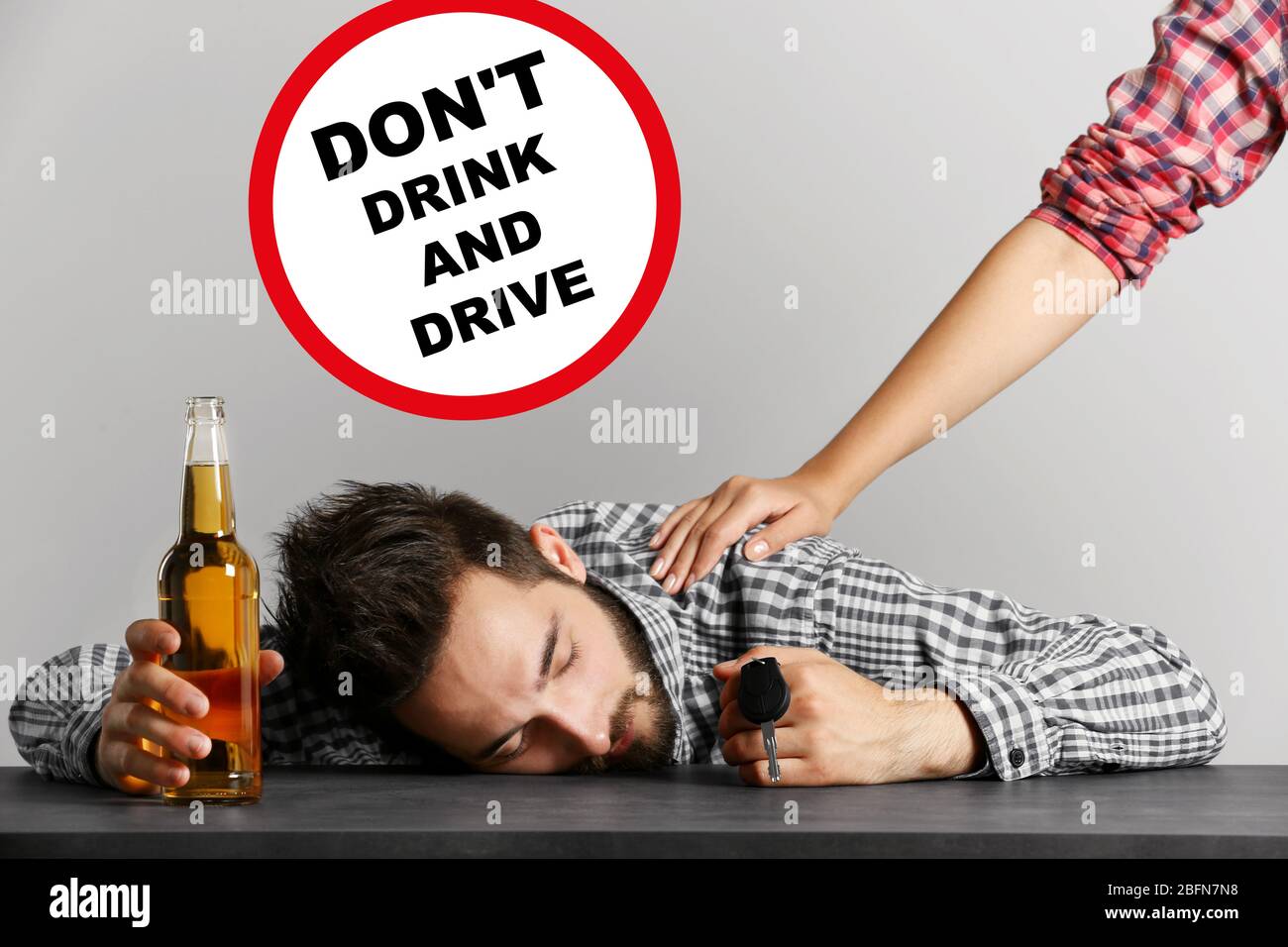 Drunk young man with car key and beer bottle at bar. Sign with text DON ...