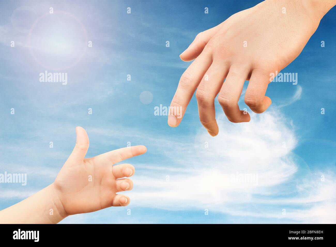 Father and child hands reaching to each other on sky background. Help ...