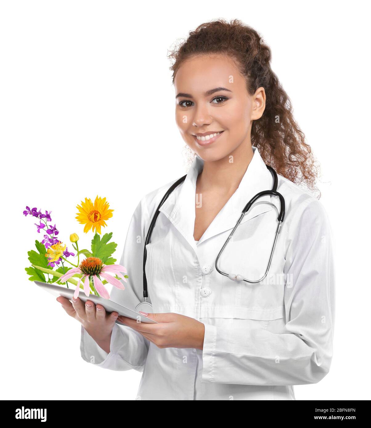 Young female doctor with tablet and flowers bouquet on white background ...