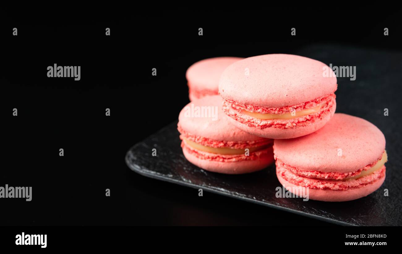 pink macaroons on a tray on a black background Stock Photo - Alamy