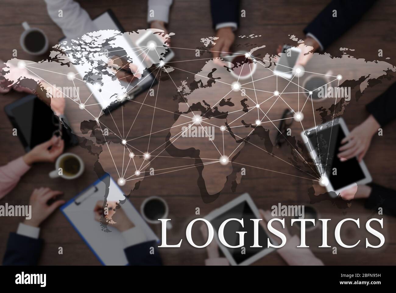 Word LOGISTICS and world map on background. People working at table ...