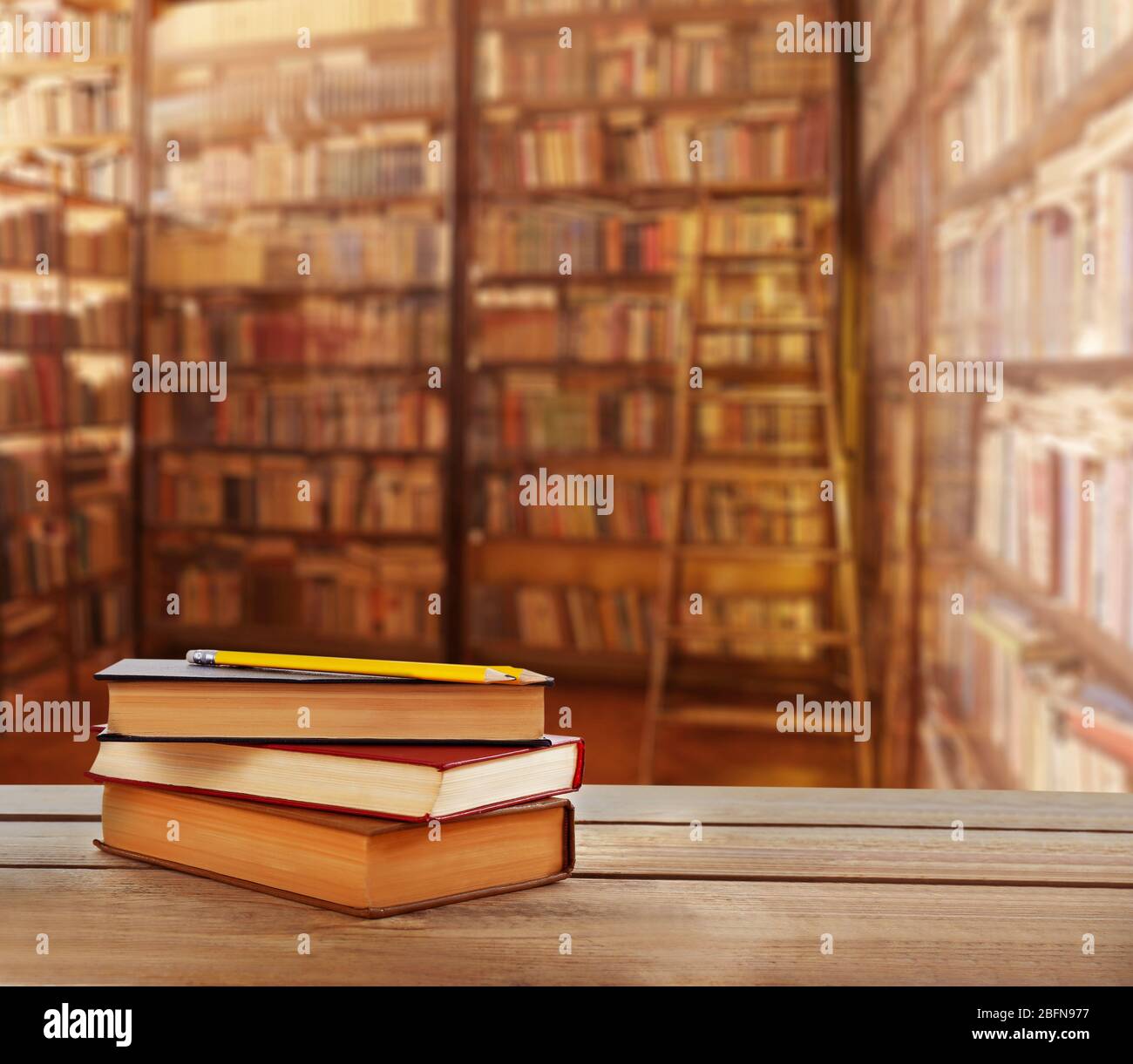 Stack of books on table at library Stock Photo - Alamy