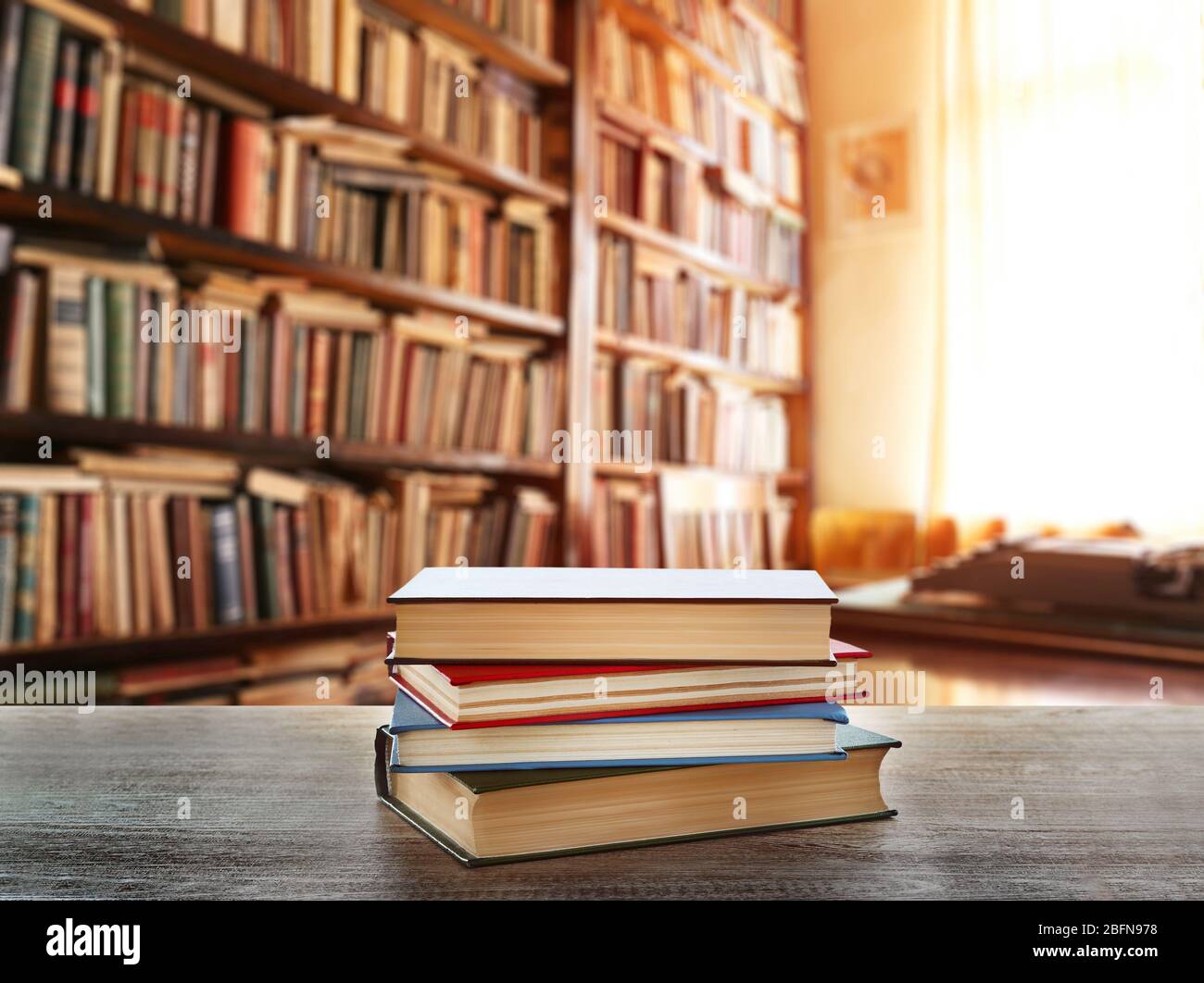 Stack of books on table at library Stock Photo - Alamy