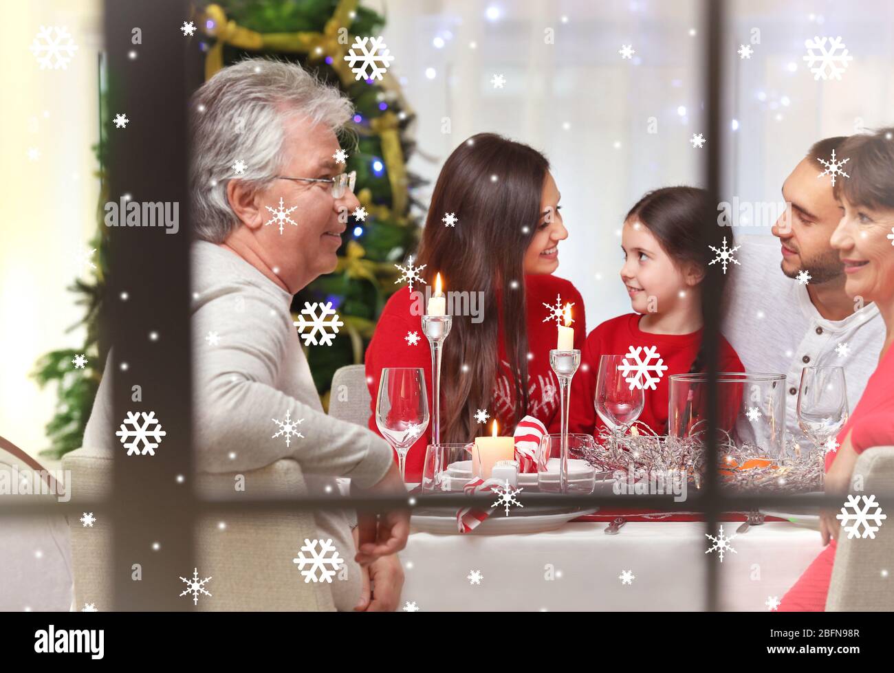 View through window on happy family during traditional Christmas dinner ...