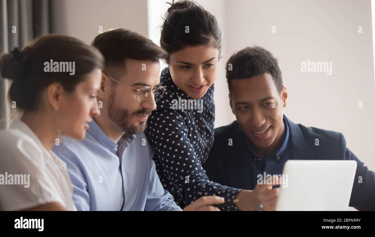 Multi-ethnic colleagues looking on computer screen working together ...
