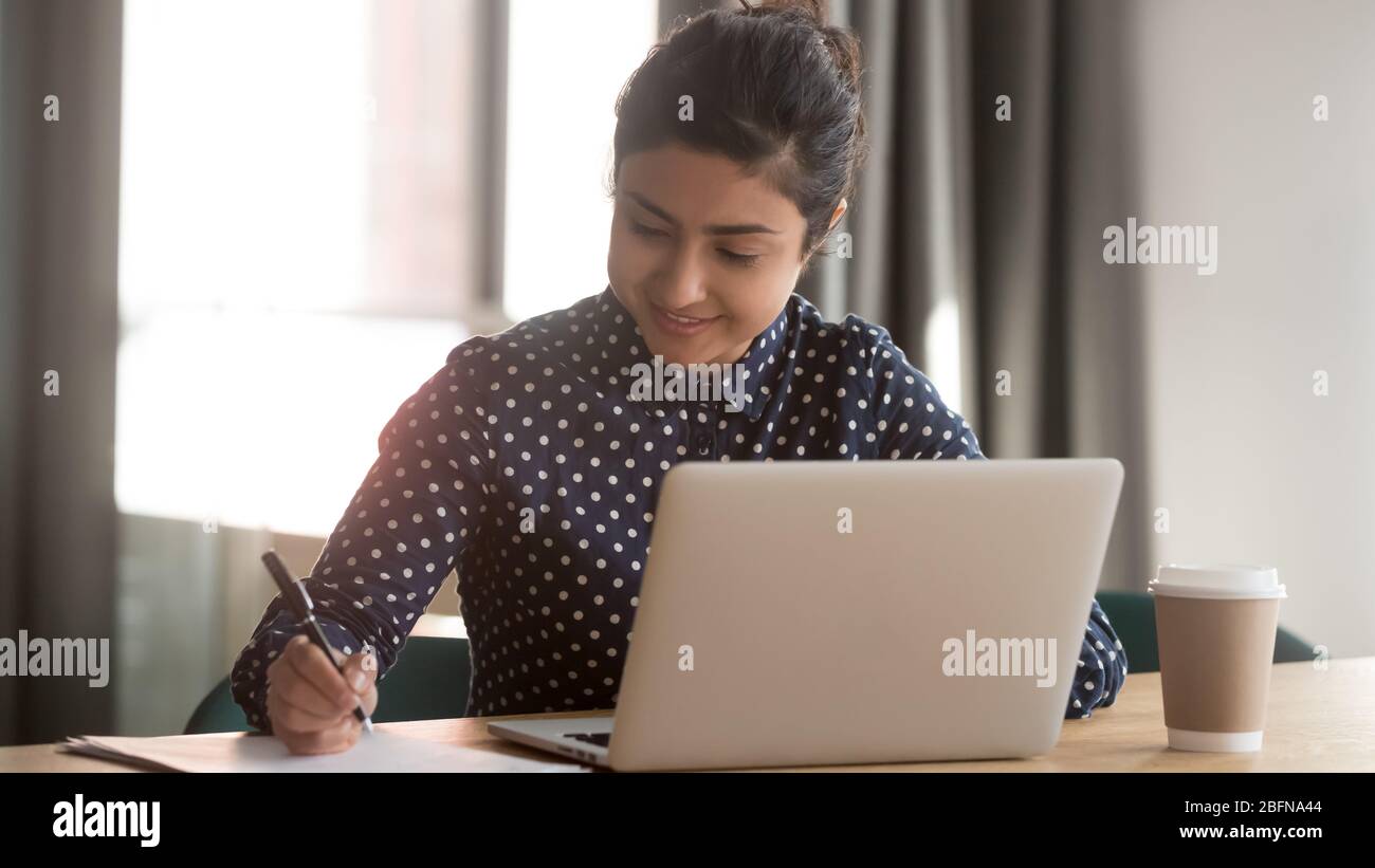 Indian businesswoman signing documents sitting at desk in workplace ...