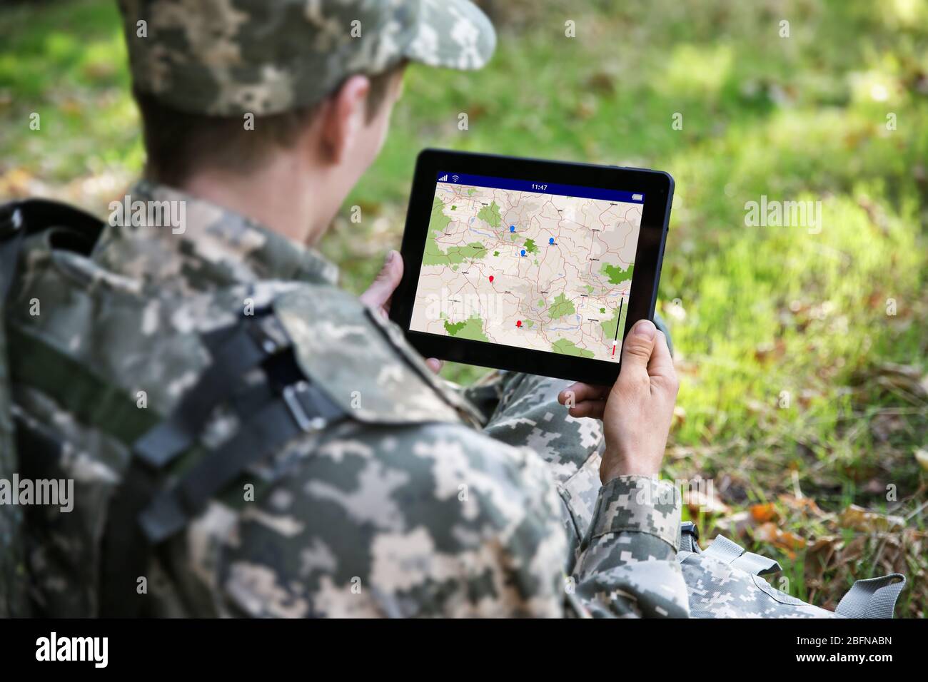 Soldier using map on tablet for orientation at forest Stock Photo - Alamy