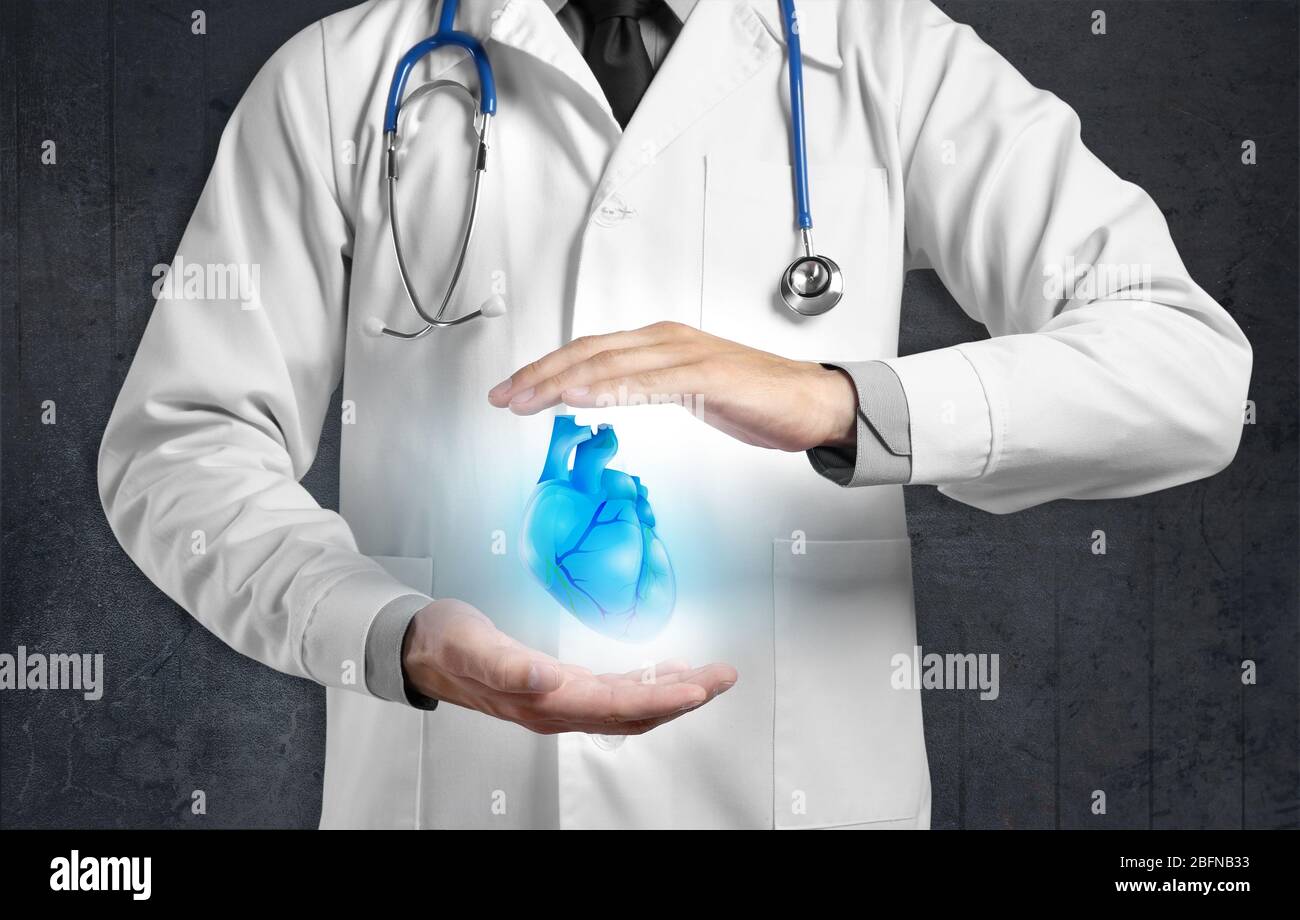 Cardiologist with heart in hands, closeup. Dark background. Cardiology ...