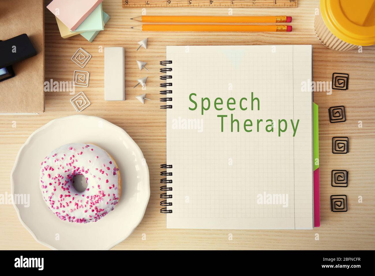 Office stationery on wooden table. Text SPEECH THERAPY on notebook page ...