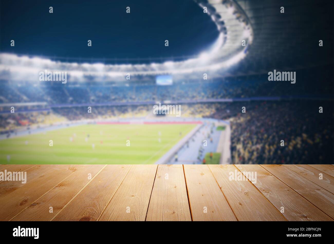 Wooden table against football stadium background Stock Photo - Alamy