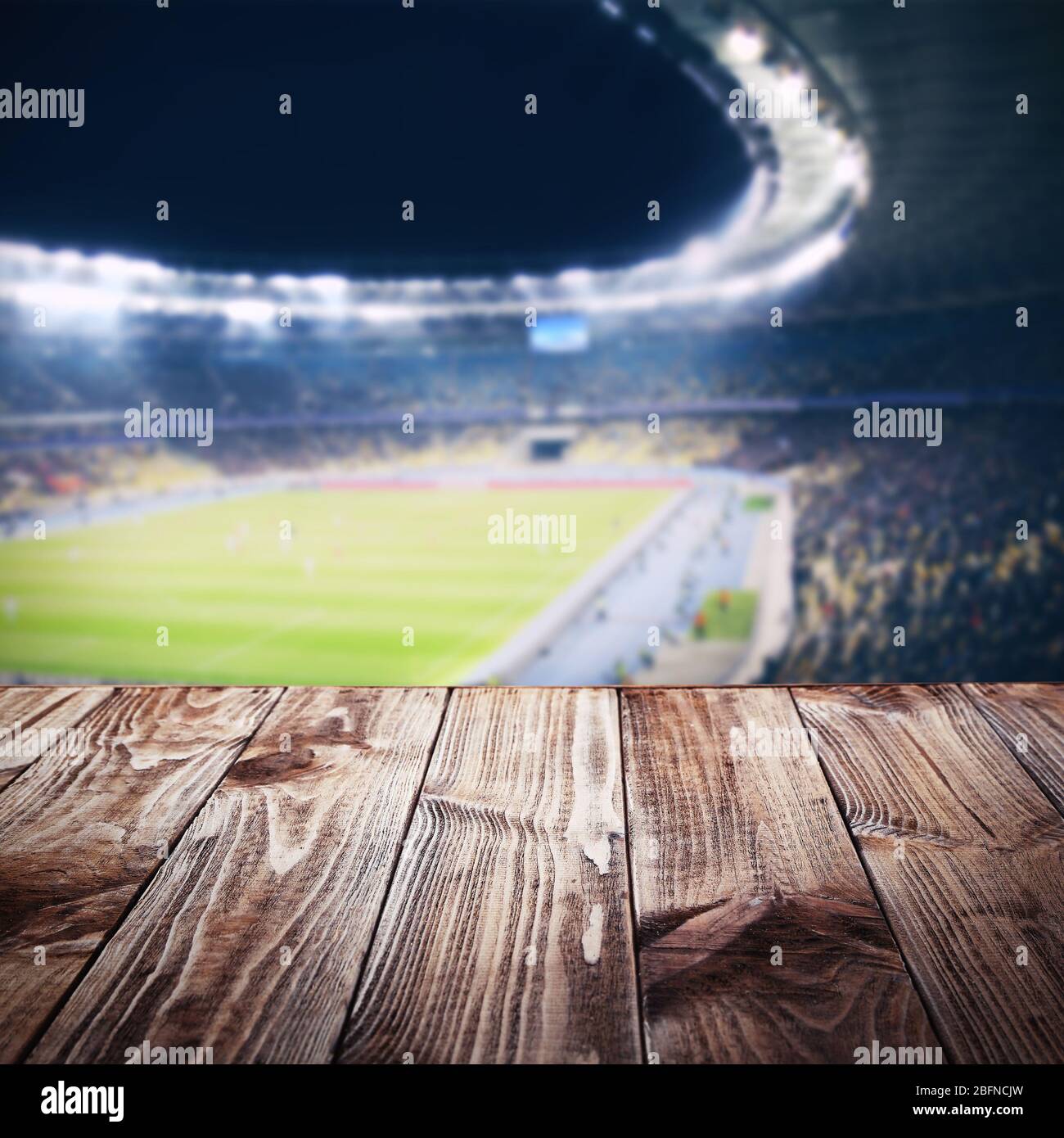 Wooden table against football stadium background Stock Photo - Alamy