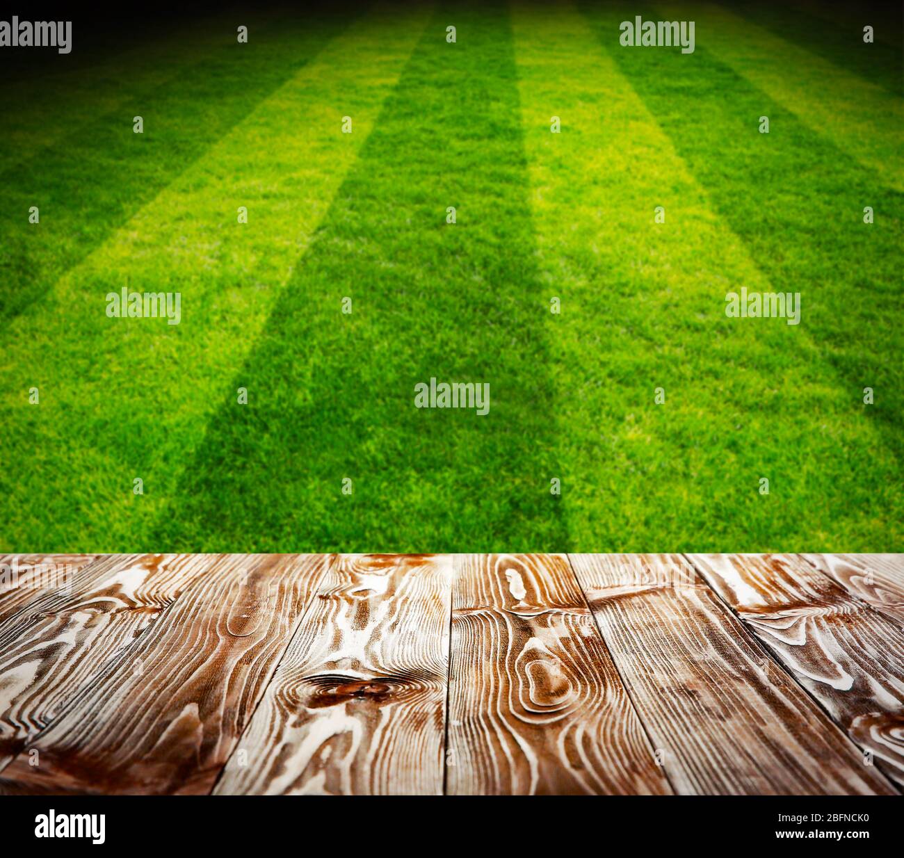 Wooden table against football field background Stock Photo - Alamy