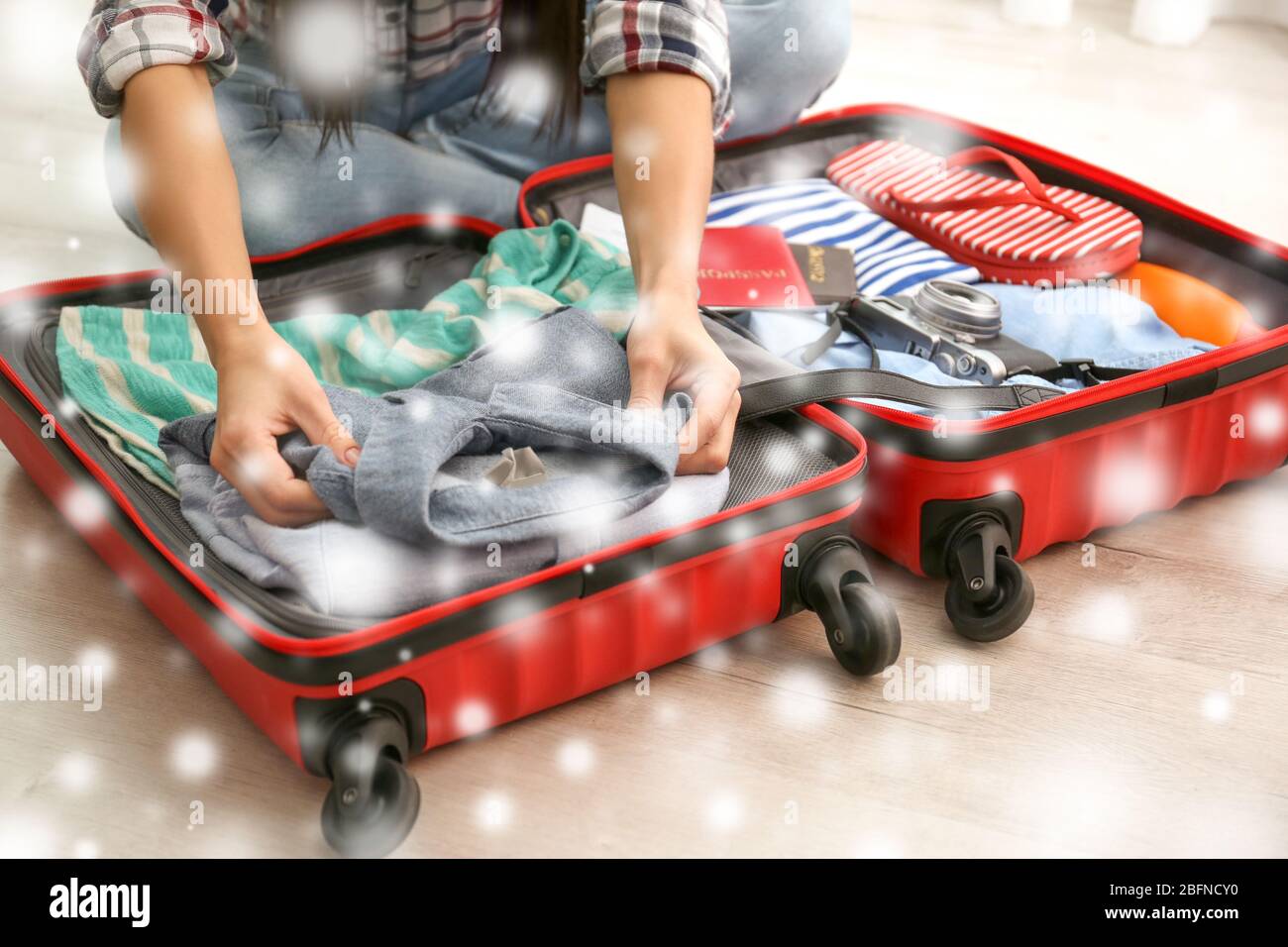 Winter vacation concept. Snowy effect on background. Woman packing ...