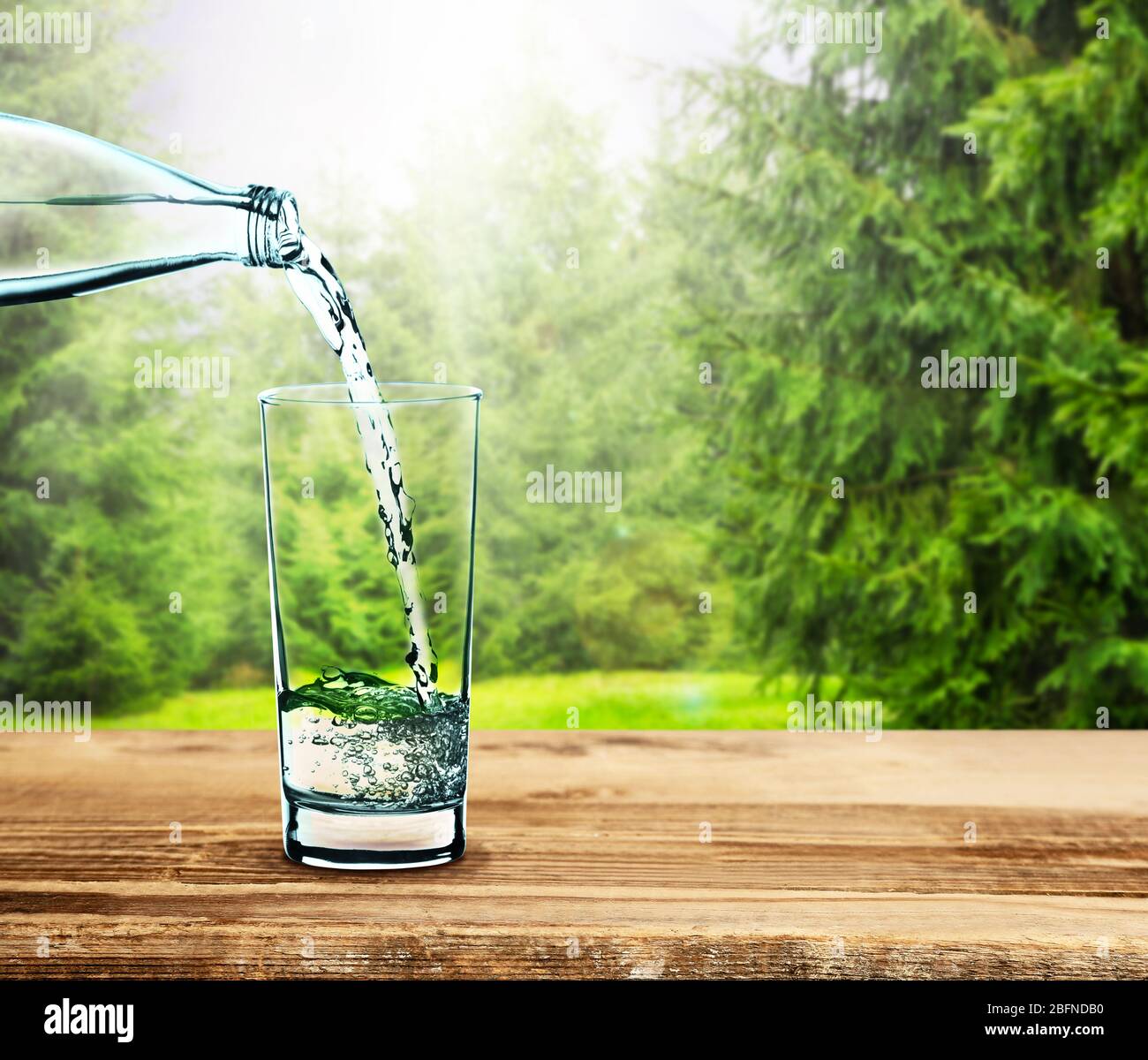 Pouring clear water into glass on nature background Stock Photo - Alamy