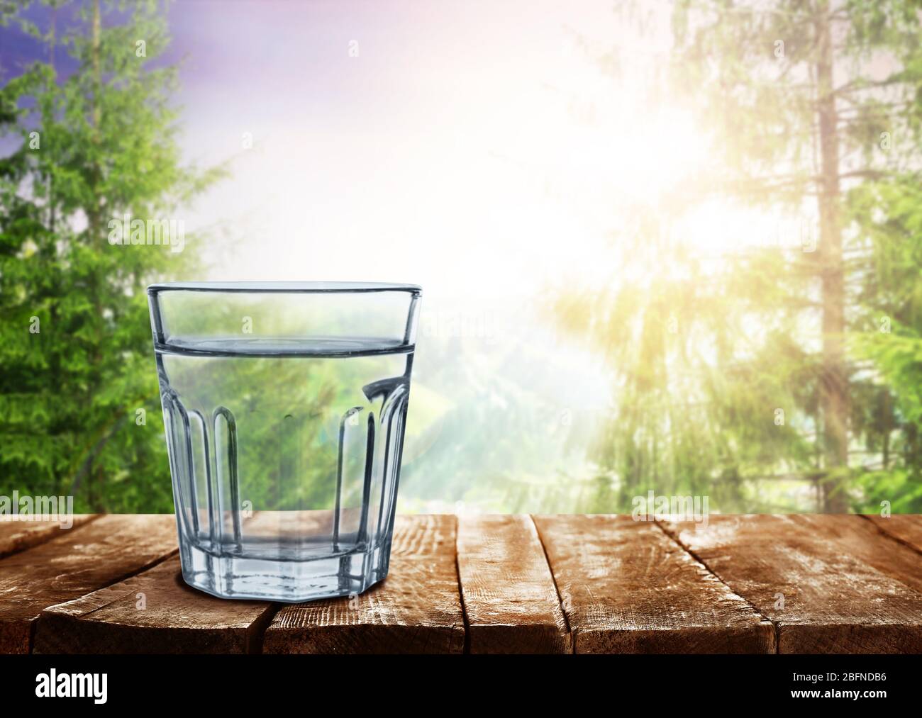 Glass of clear water on wooden table against nature background Stock ...