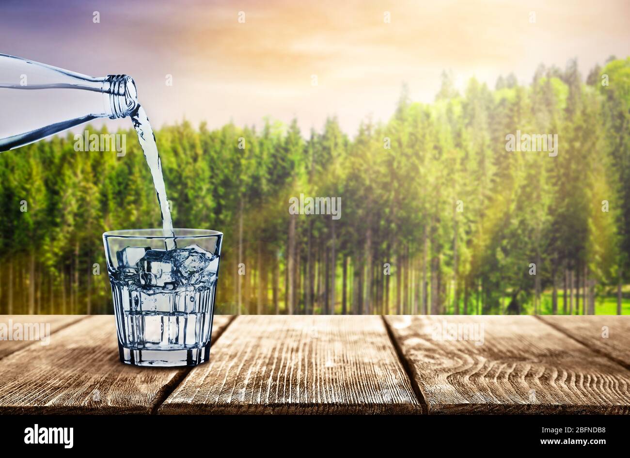 Pouring clear water into glass on nature background Stock Photo - Alamy