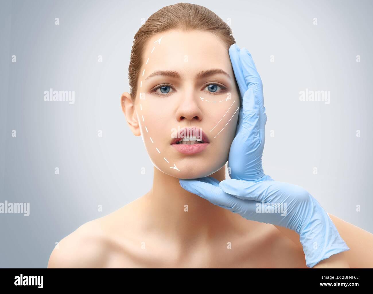 Plastic surgery concept. Doctor examining female face, light background ...