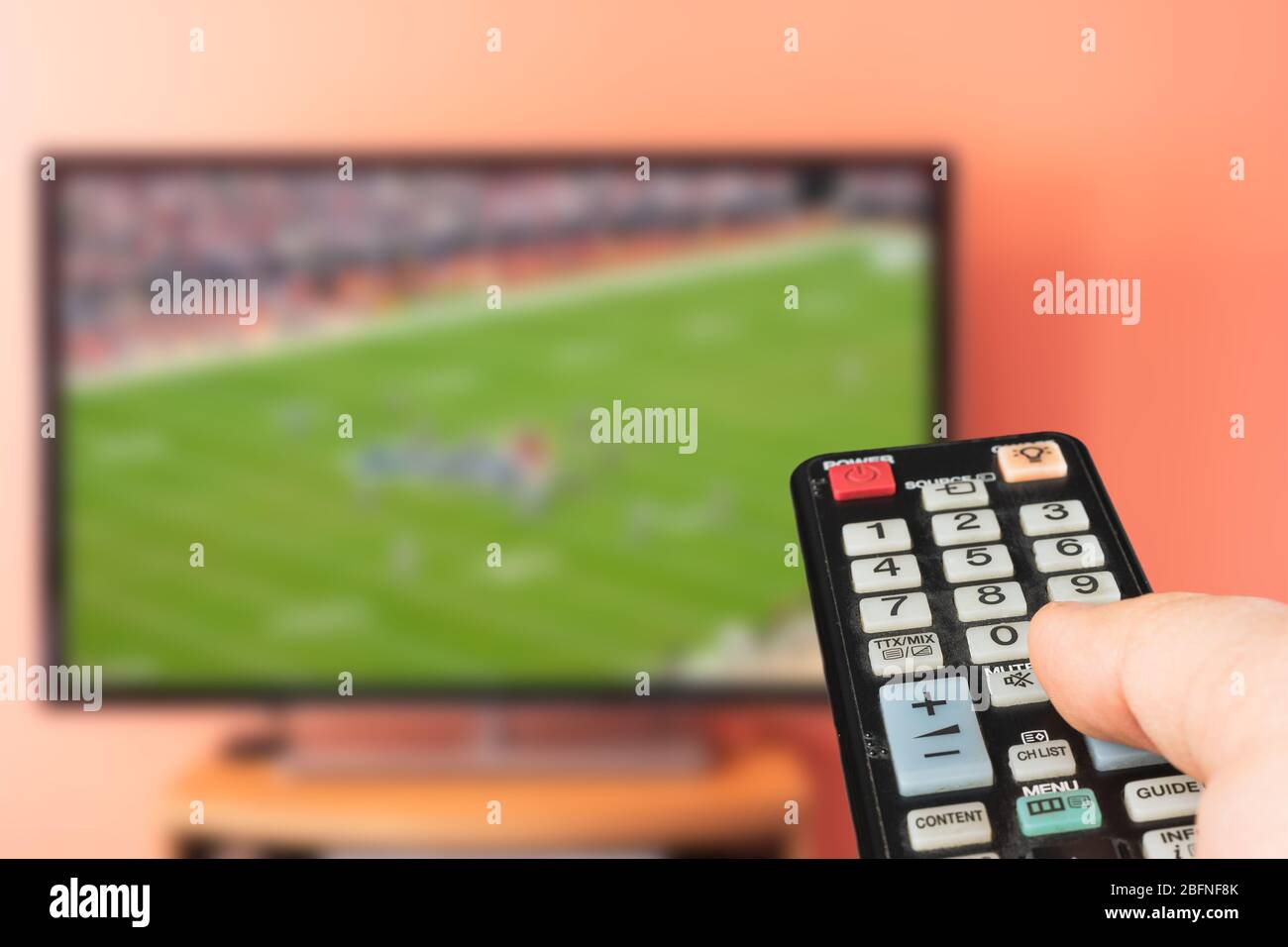 Caucasian man watching american football game on TV at home. Changing ...