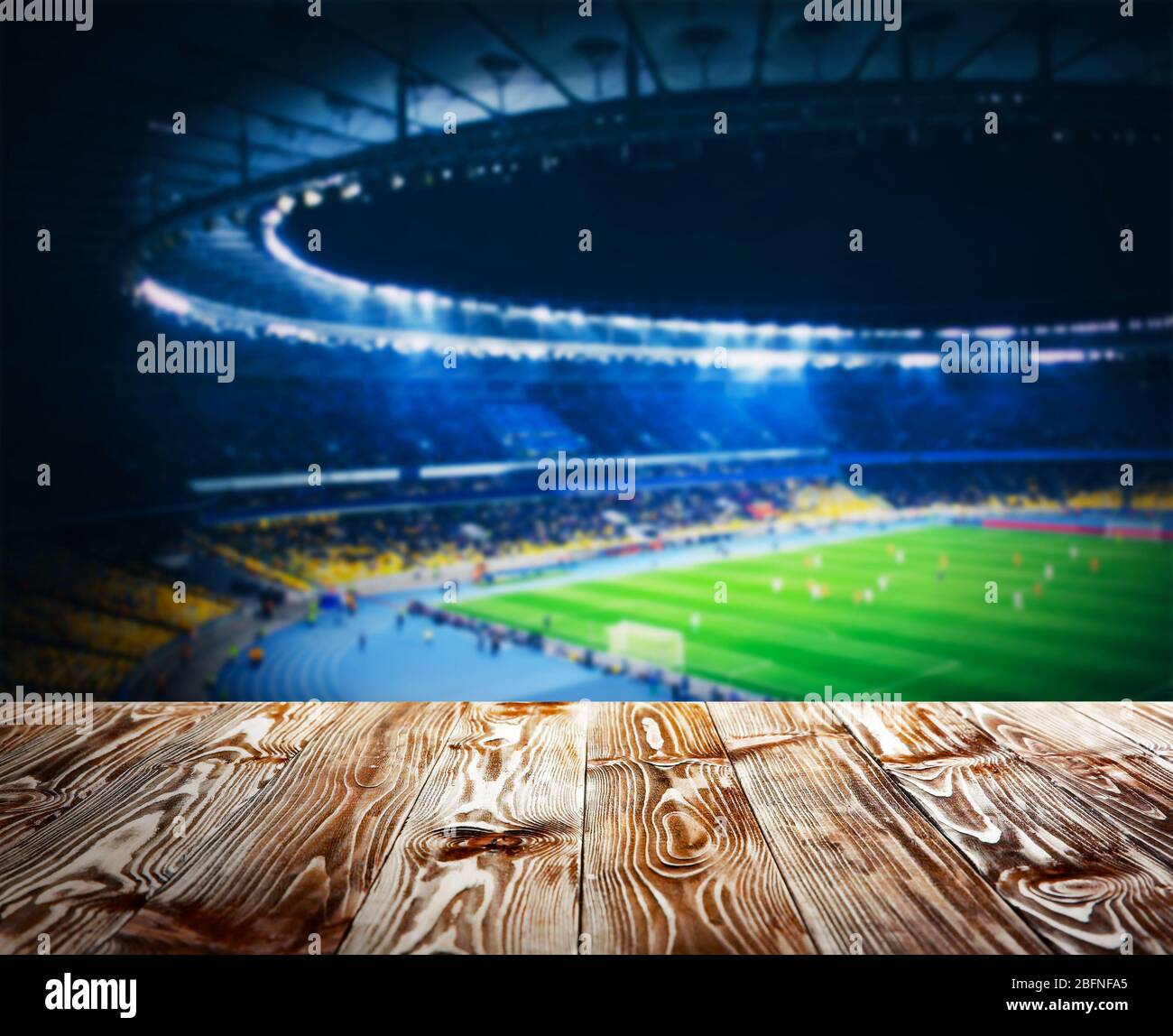 Wooden table against football stadium background Stock Photo - Alamy