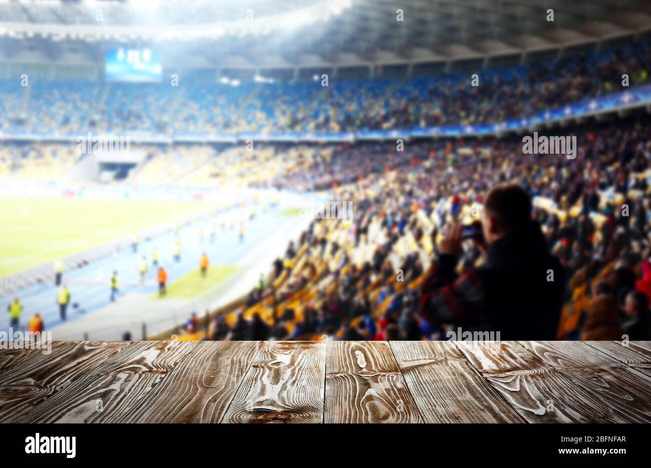 Wooden table against football stadium background Stock Photo - Alamy