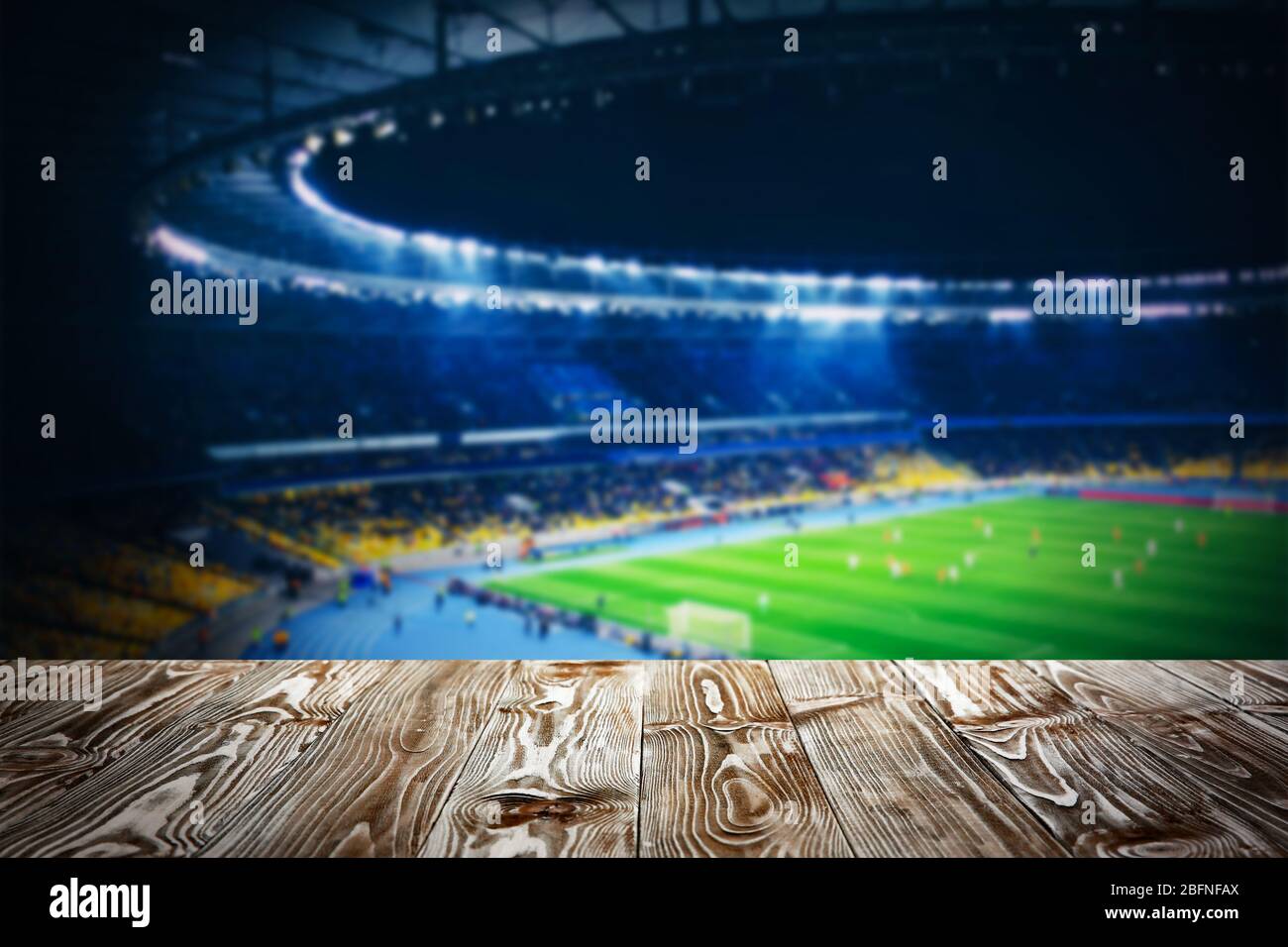Wooden table against football stadium background Stock Photo - Alamy