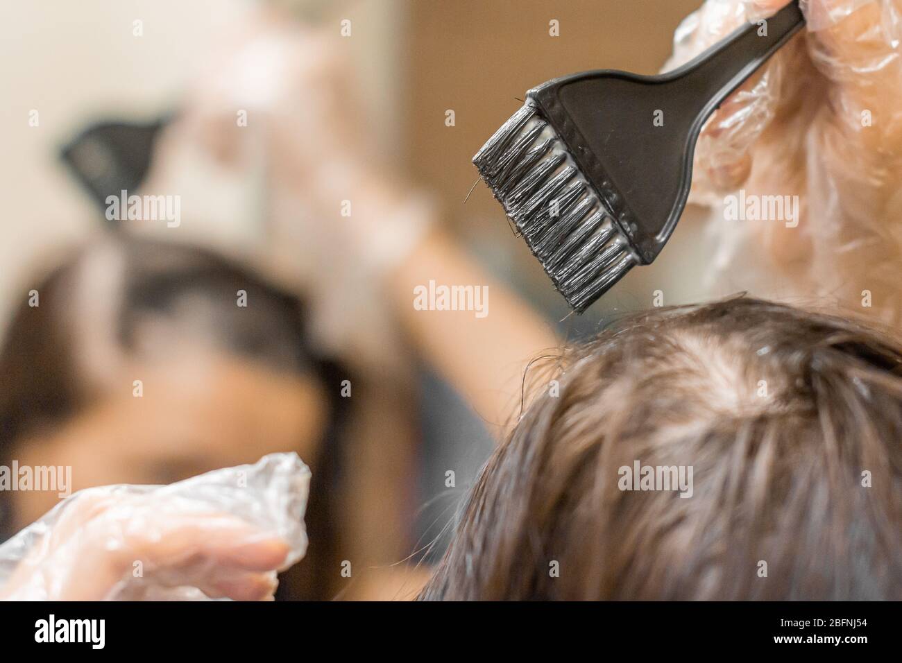 Closeup woman hands dyeing hair using a black brush. Colouring of white ...