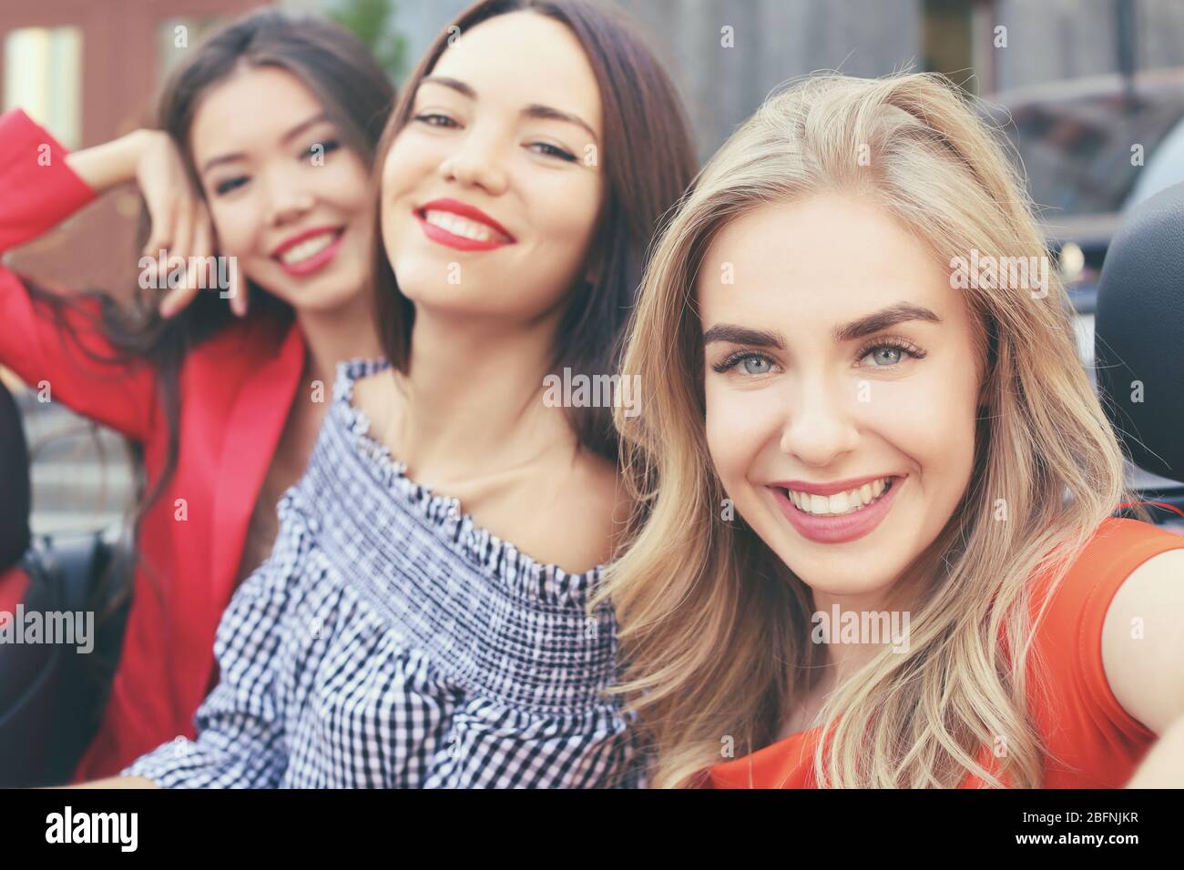 Beautiful young women sitting on back seat in car Stock Photo - Alamy