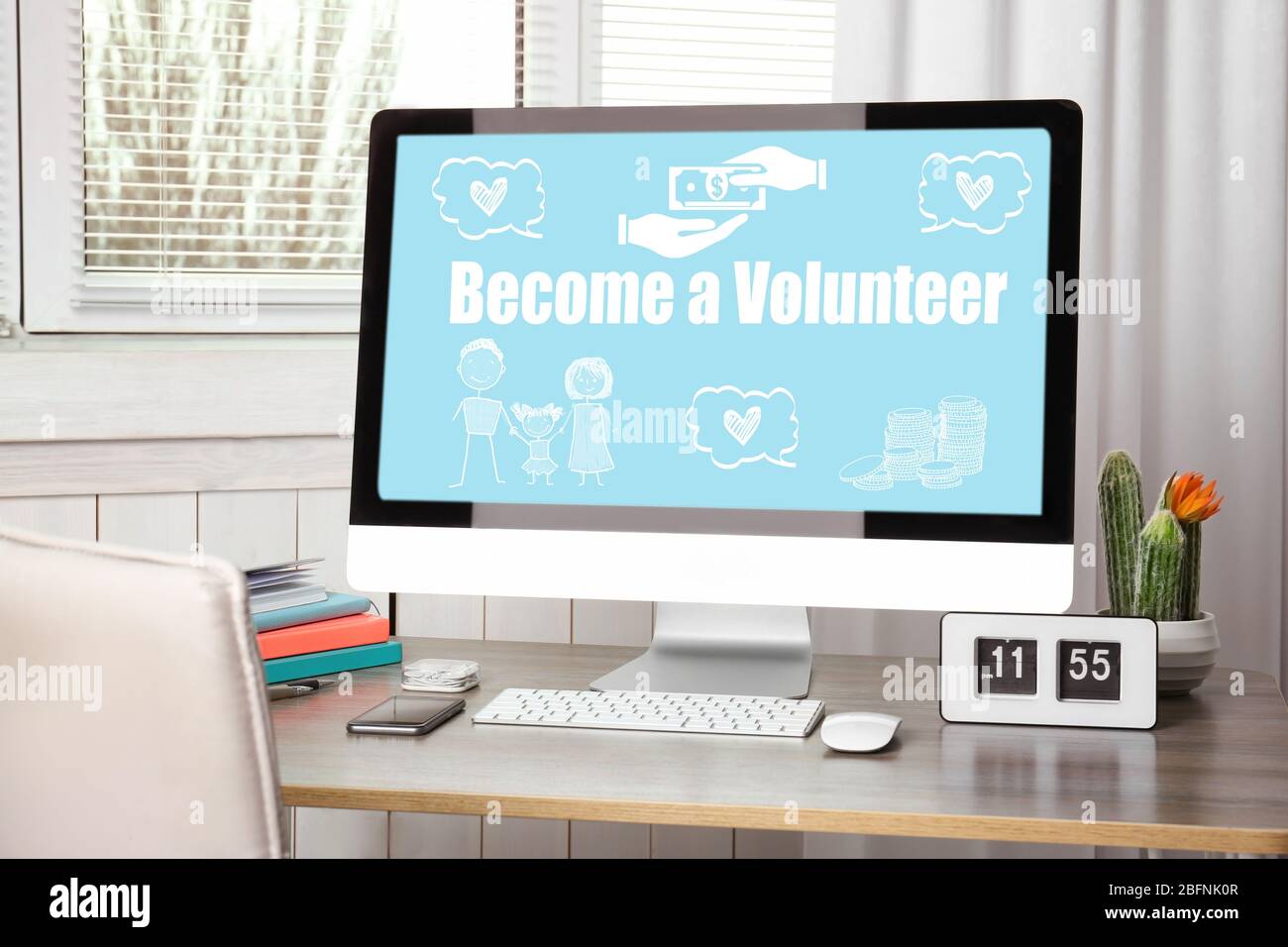 Workplace with computer and text BECOME A VOLUNTEER on screen in office ...
