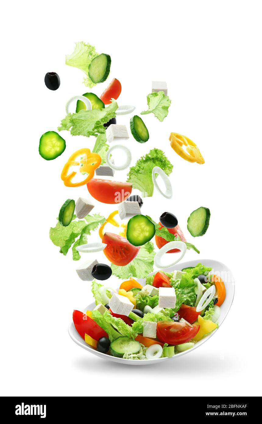 Sliced vegetables falling into bowl with salad on white background ...
