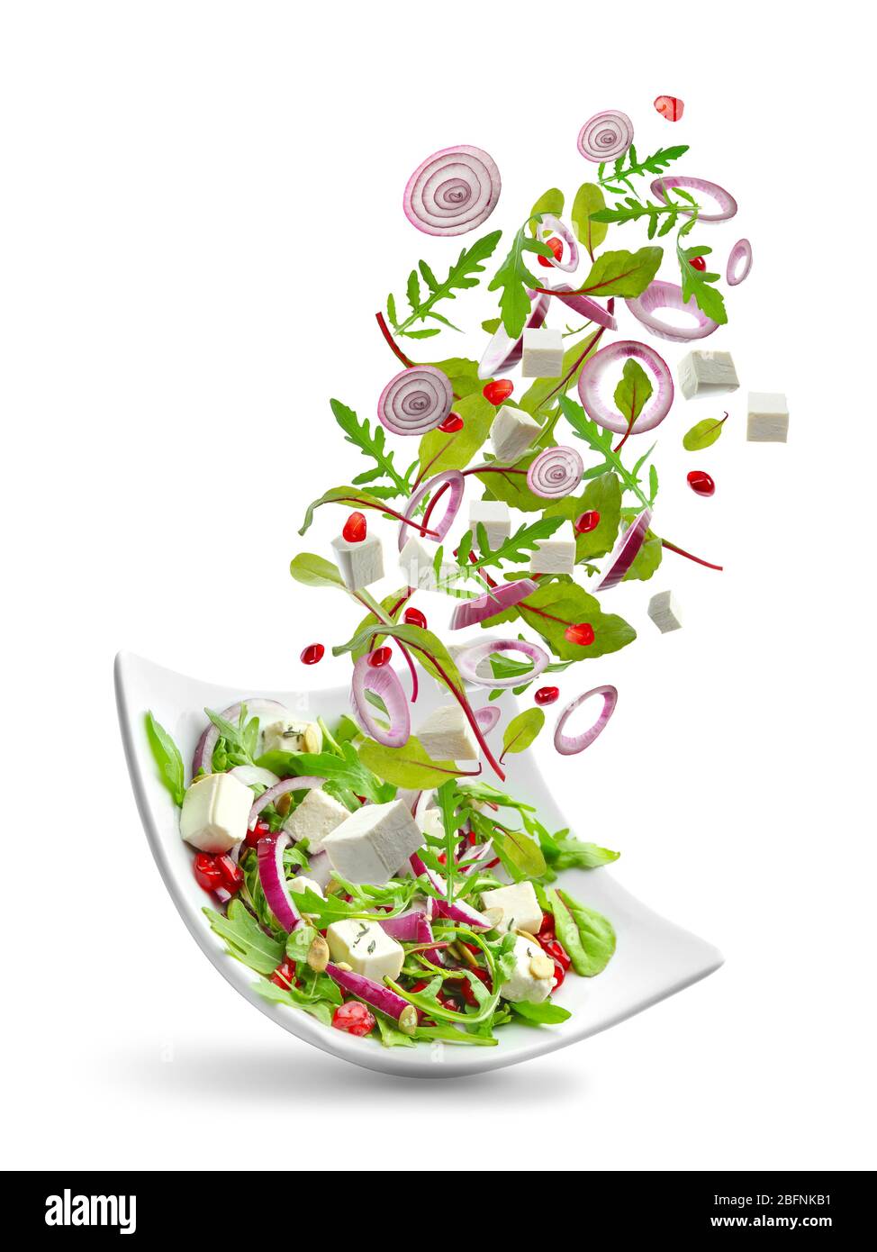 Ingredients falling into bowl with salad on white background Stock ...