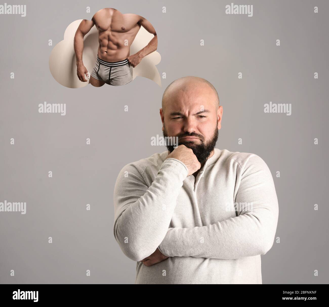 Overweight man dreaming about muscular body on grey background. Weight ...